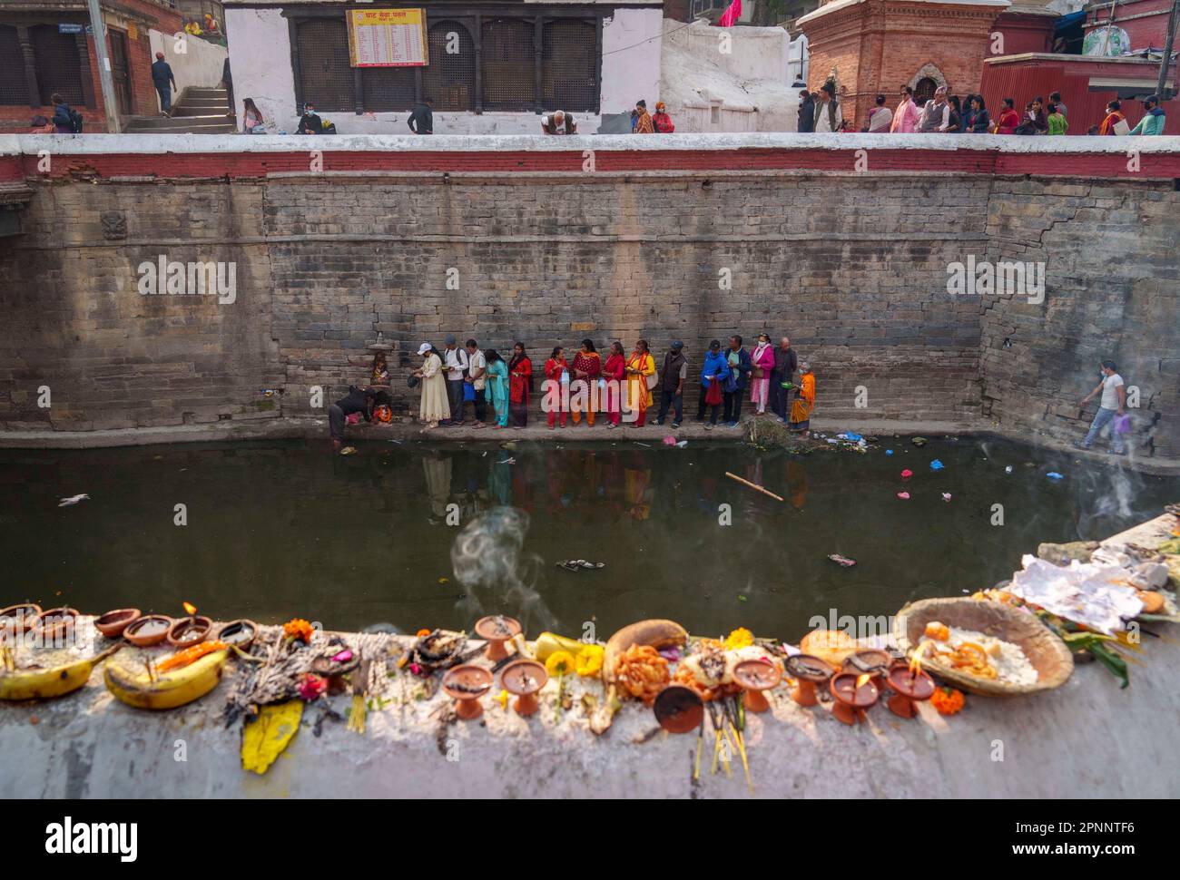 Hindu devotees queue up on a narrow ledge on the banks of the Bagmati ...
