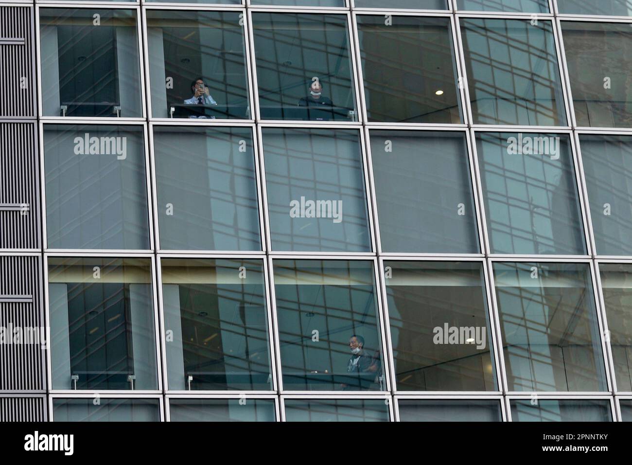 People are seen through the window of a high-rise building in Tokyo's ...