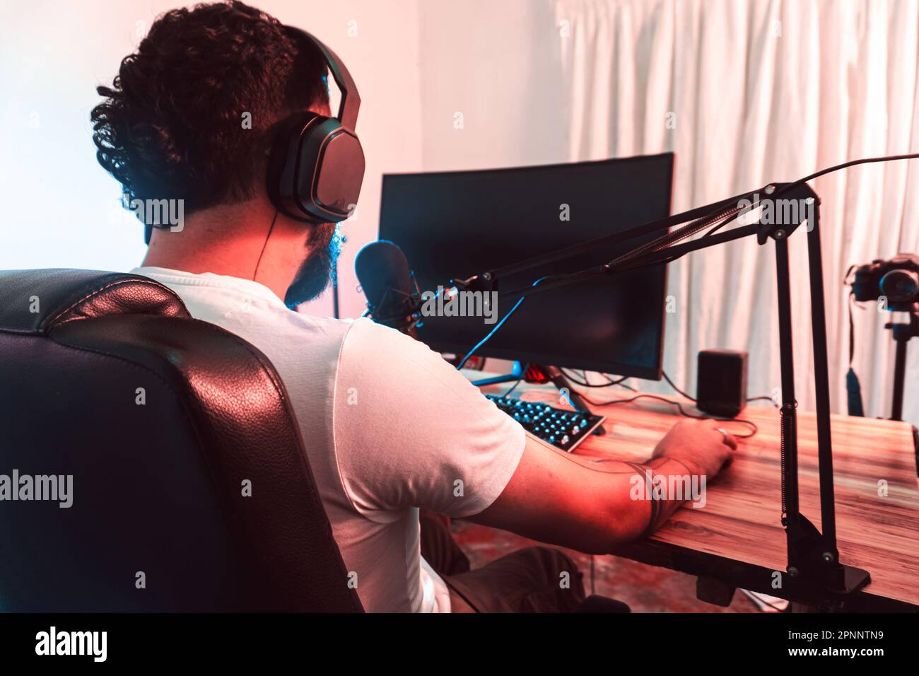 Professional gamer with headphones and a microphone playing a online ...