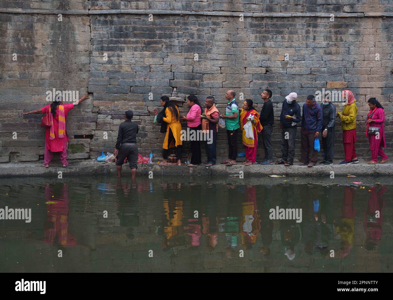 Hindu devotees queue up on a narrow ledge on the banks of the Bagmati ...