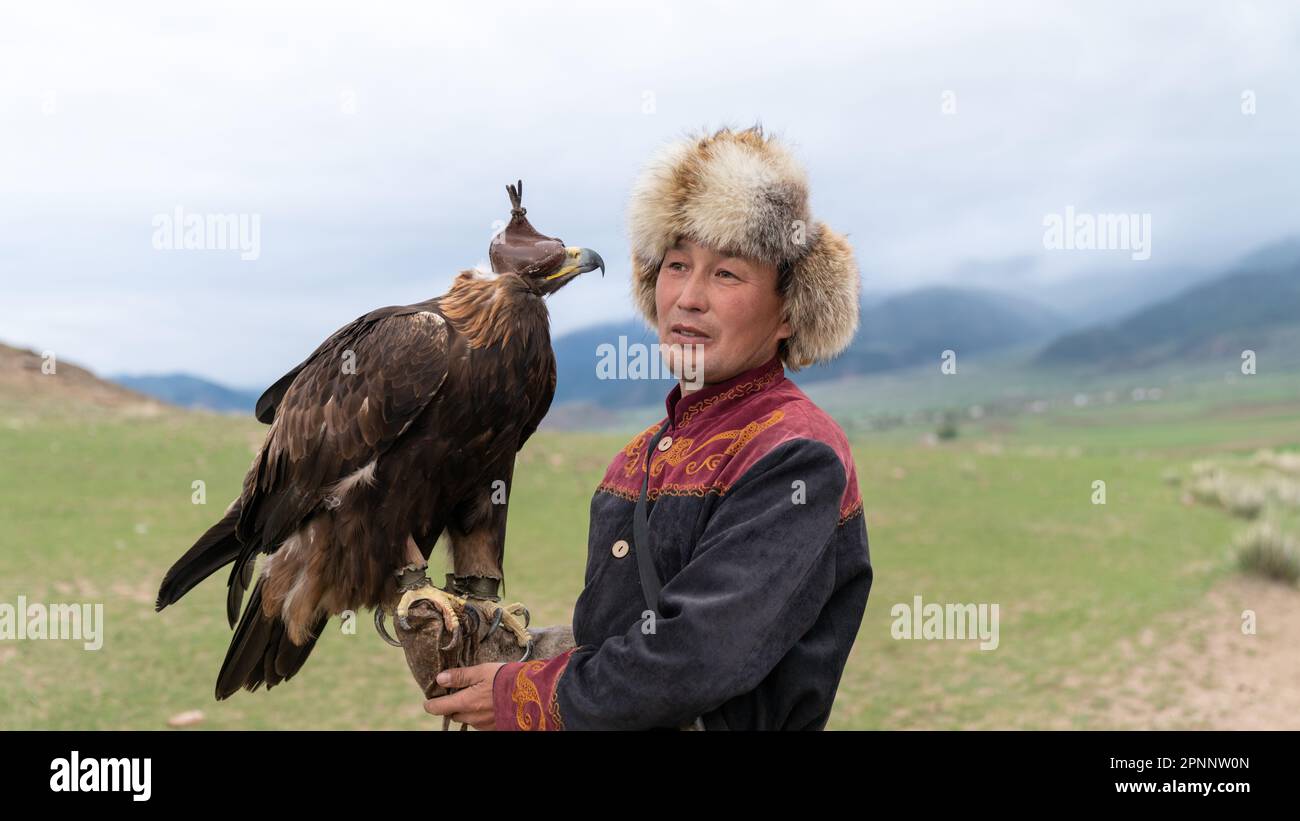 Issyk Kul, Kyrgyzstan - May 2022: Eagle trainer and his golden eagle, skilled in training eagles ...