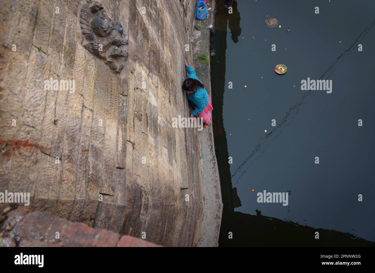 A Hindu devotee makes her way back through a narrow ledge on the banks ...