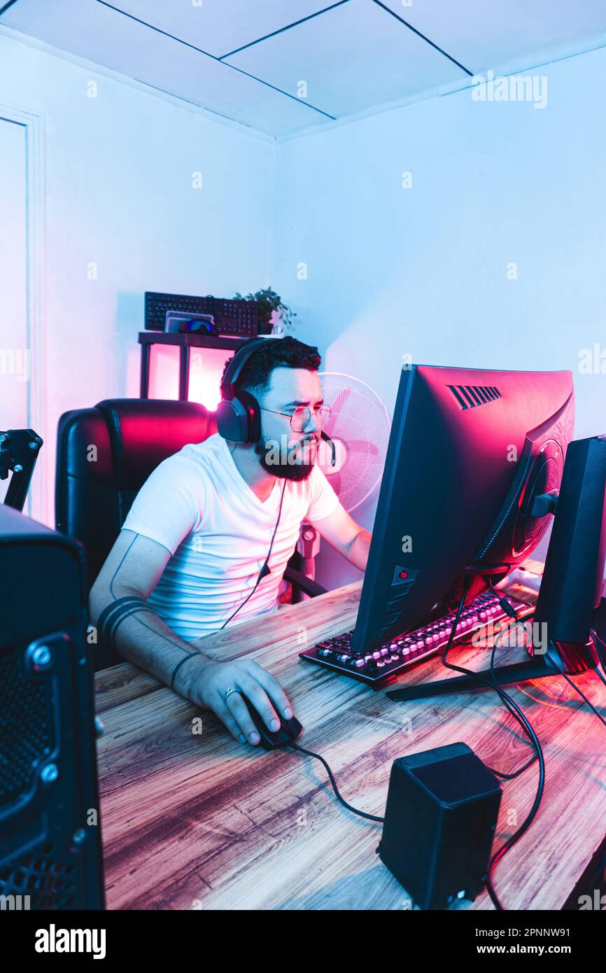 A Hispanic professional gamer wearing headphones immersed in playing an ...