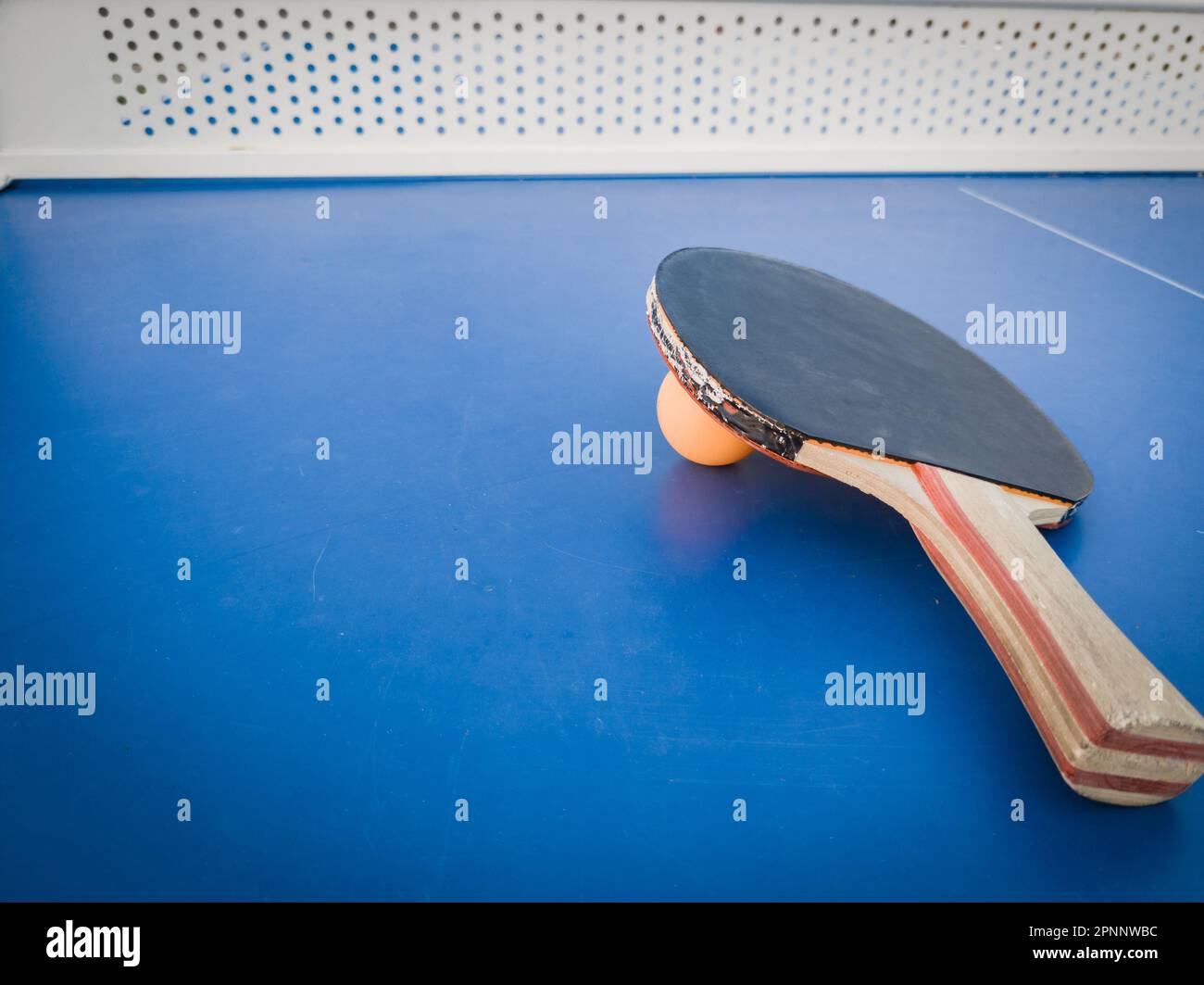 A professional ping pong paddle rests atop a vibrant blue ping pong ...