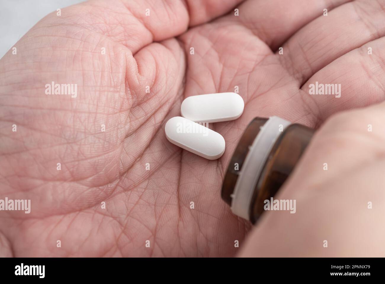 Man taking painkiller white pills on male hand pouring tablets from ...