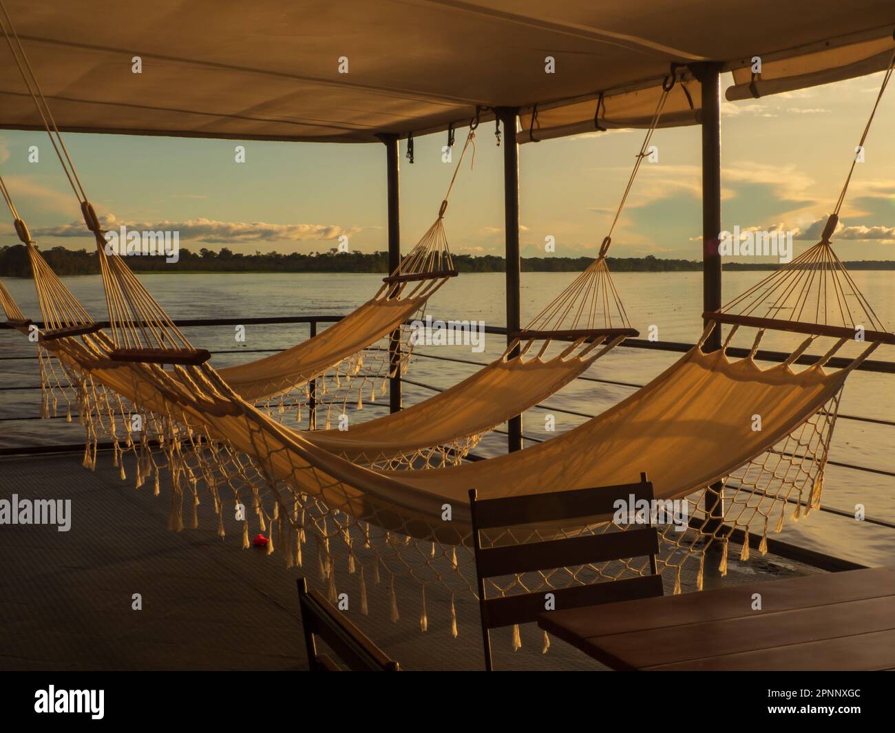 Sunset and hammocks on board a luxury tourist ship sailing the Amazon ...