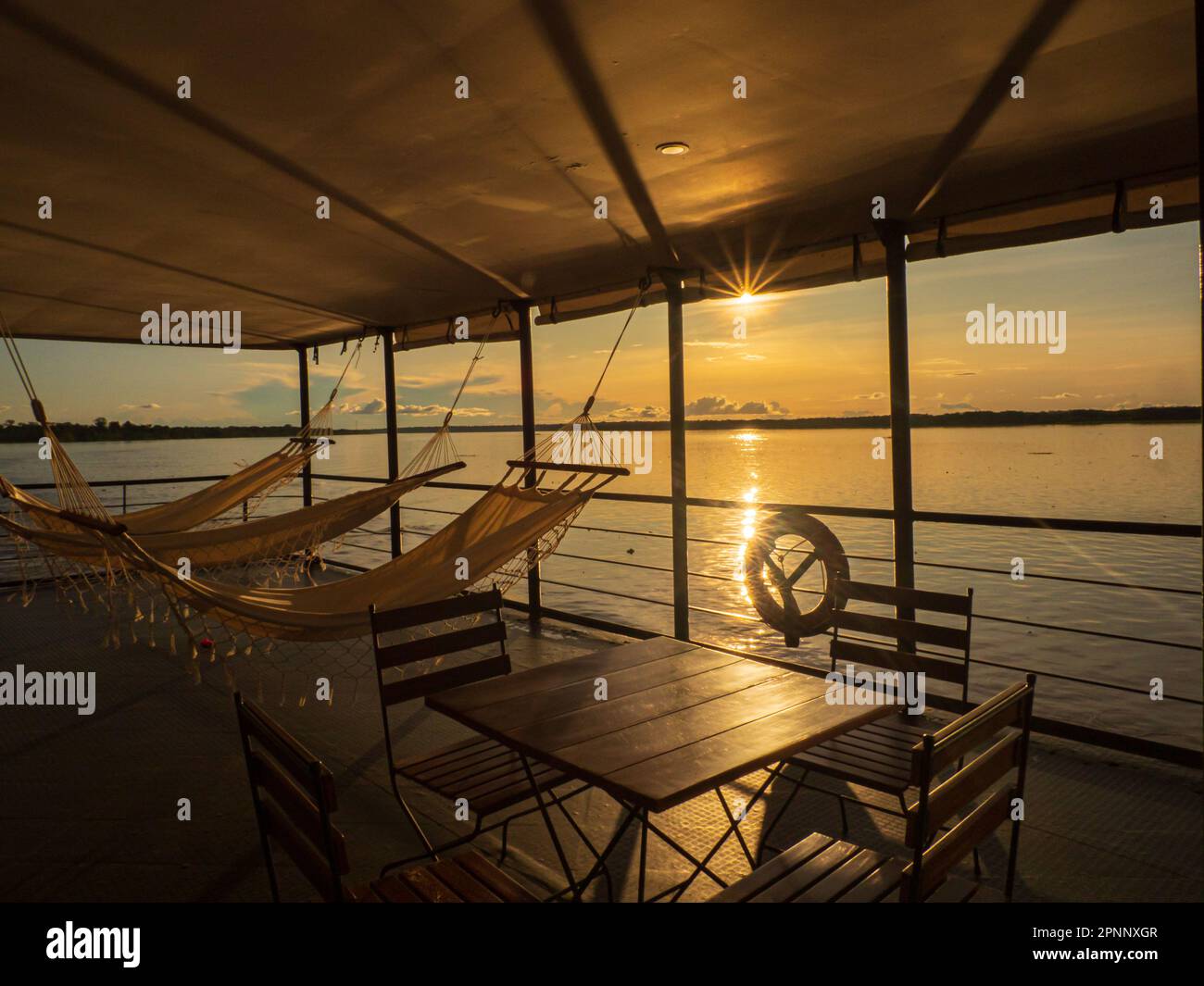 Sunset and hammocks on board a luxury tourist ship sailing the Amazon ...
