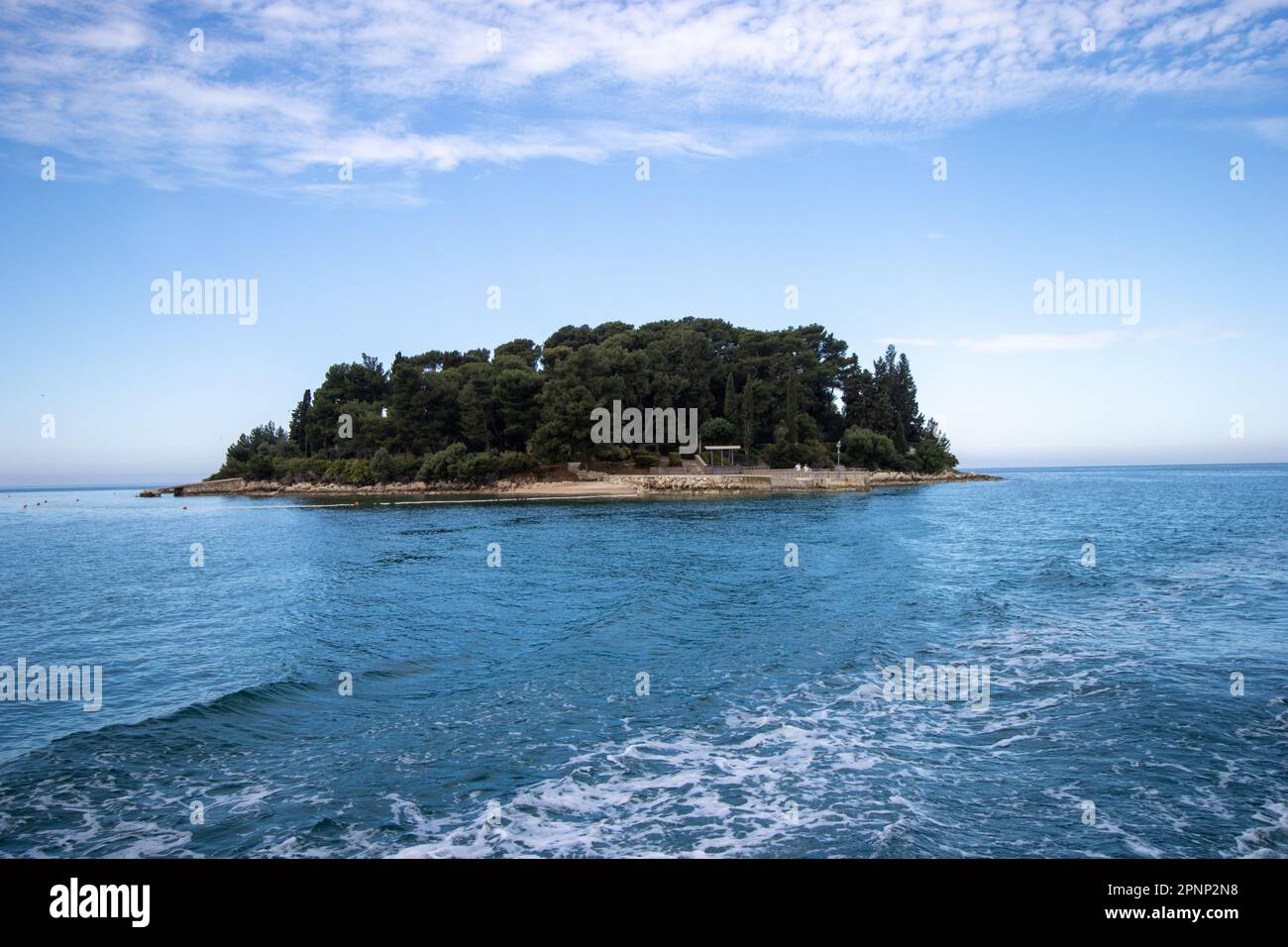 small island near Rovinj, Croatia with a clear blue sky and a calm blue ...