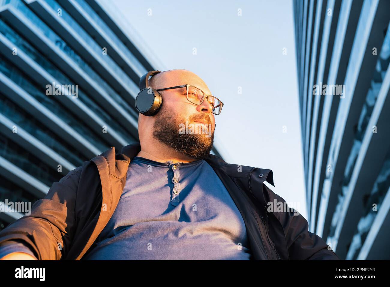 Bearded plus size man in glasses listening to music with headphones ...