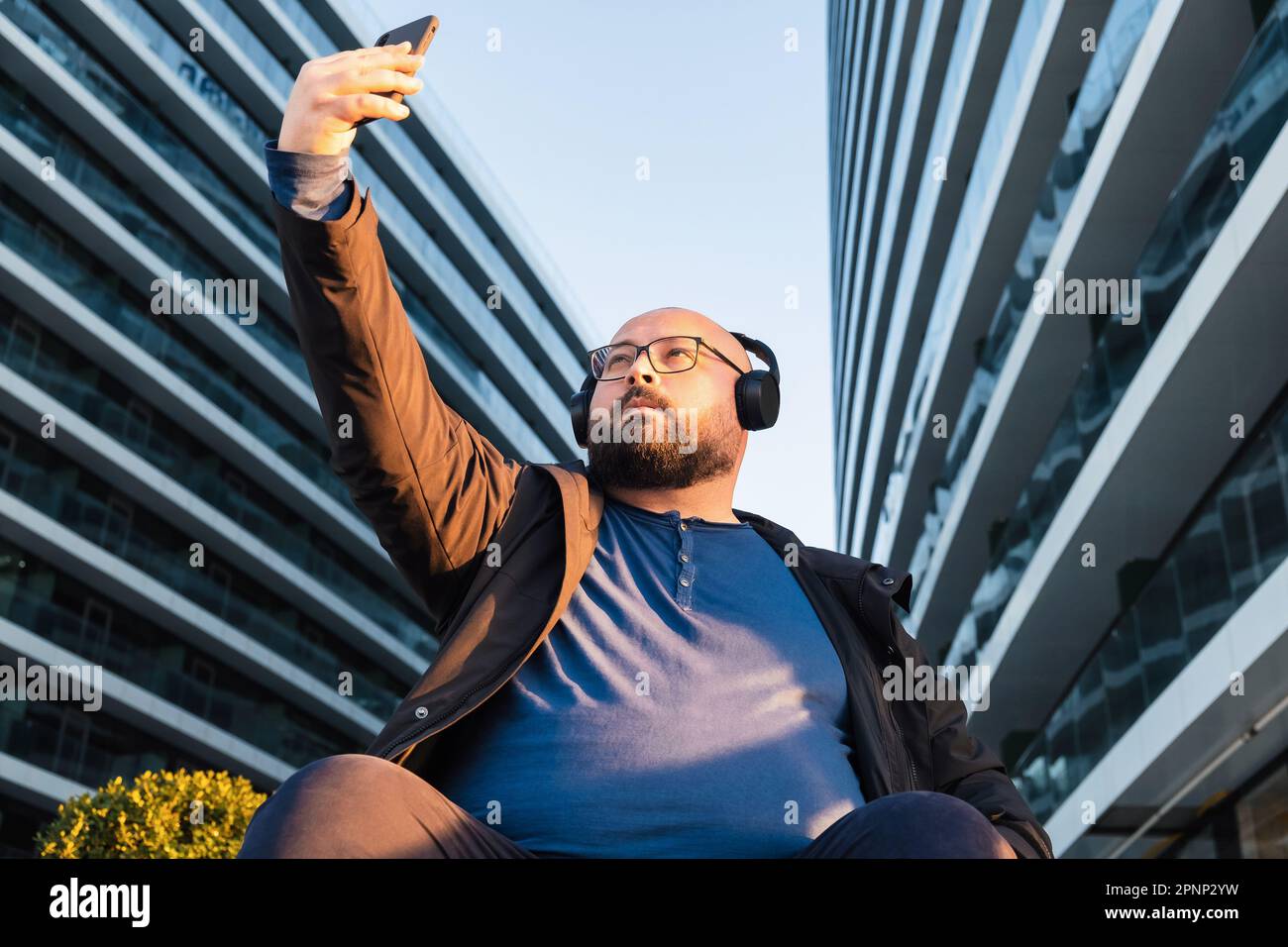 Bearded plus size man in glasses taking selfie while listening music ...