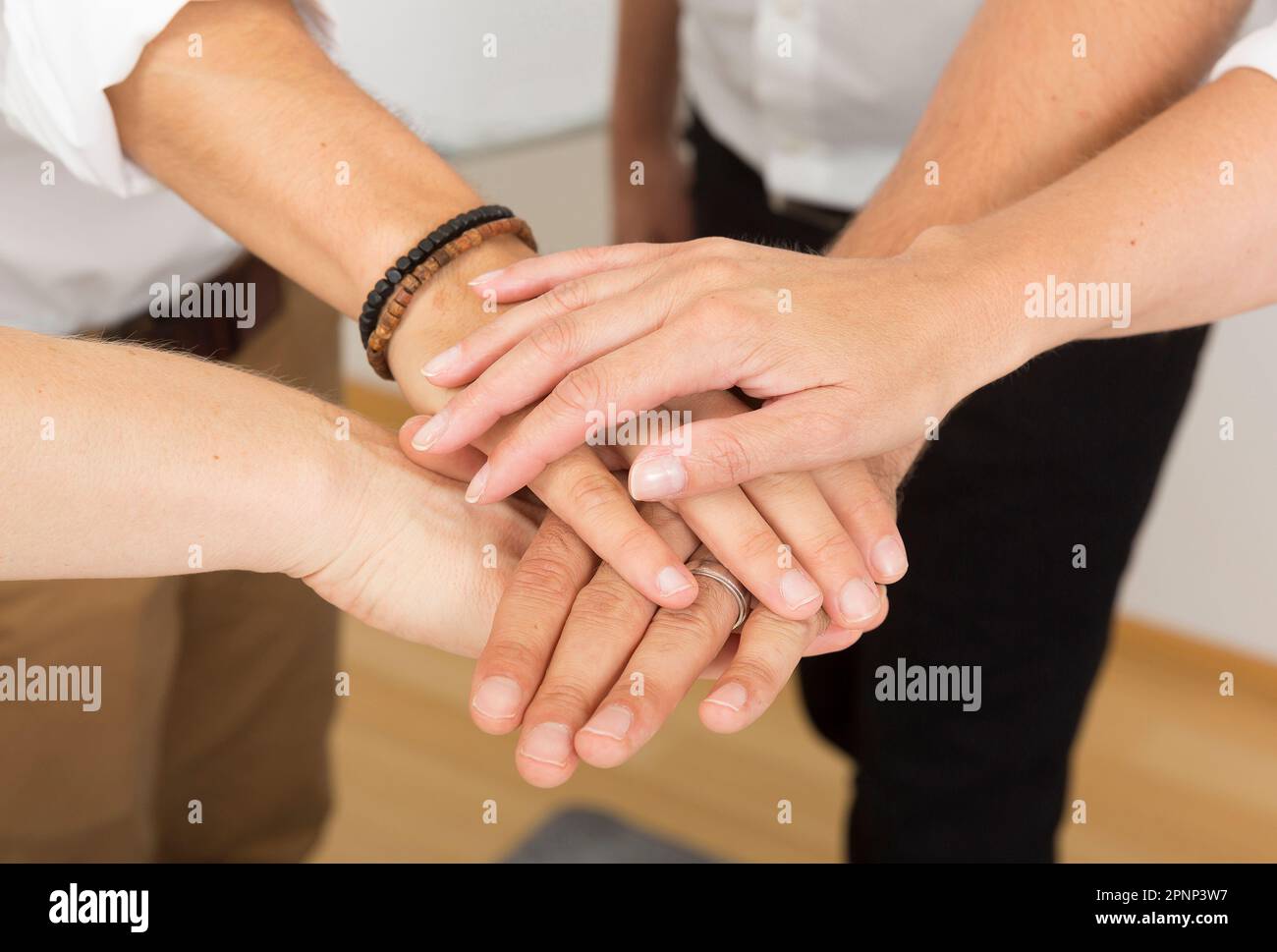Four hands on top of each other as a sign of cohesion Stock Photo - Alamy