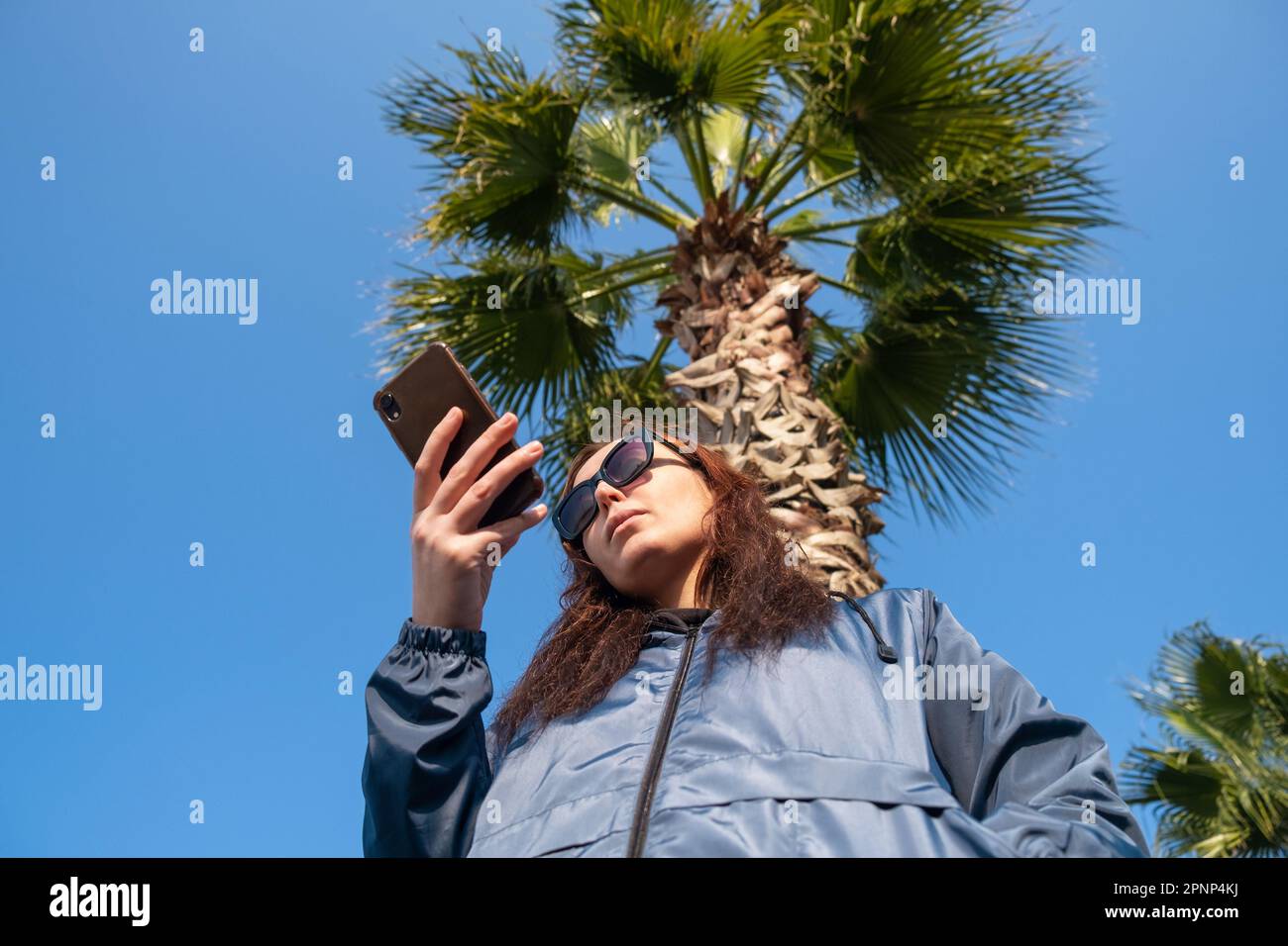 Young attractive caucasian woman in sunglasses using smartphone or ...
