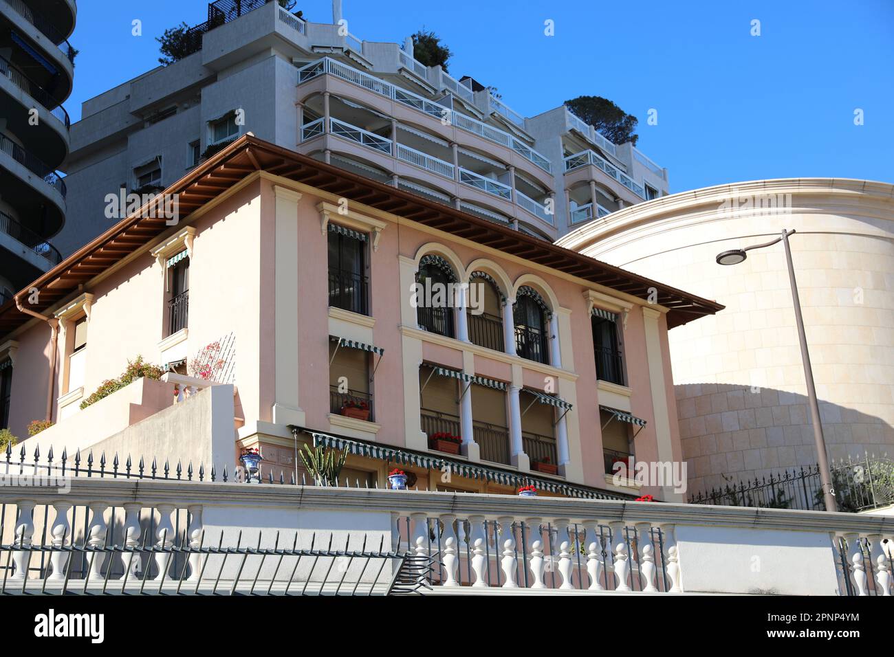 Low-angle view of a luxurious two-story pink house surrounded by ...