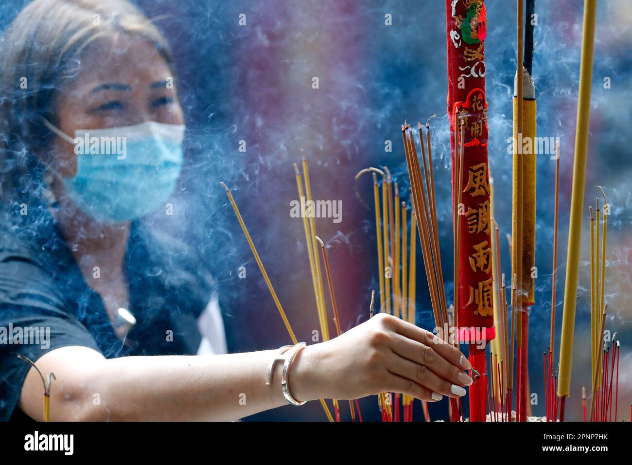 Ba Thien Hau Chinese Temple. Buddhist woman praying with incense sticks ...