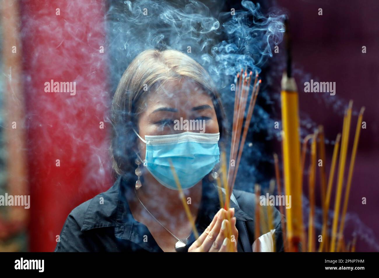 Ba Thien Hau Chinese Temple. Buddhist woman praying with incense sticks ...