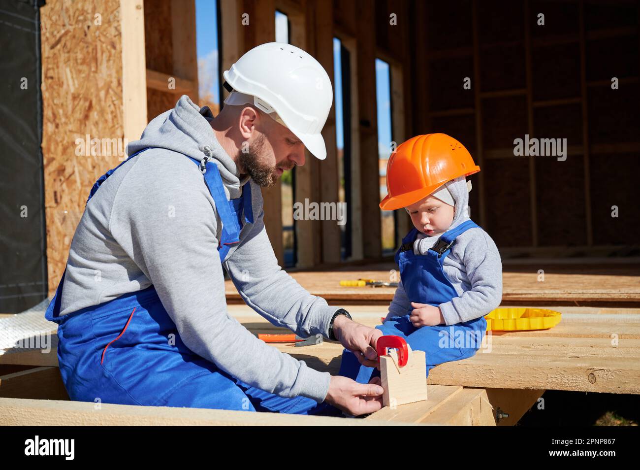 Father with toddler son building wooden frame house. Male builder ...