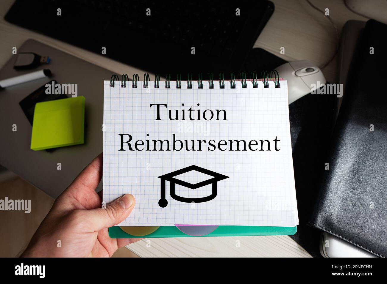 Tuition reimbursement word on notebook holding man against desktop ...