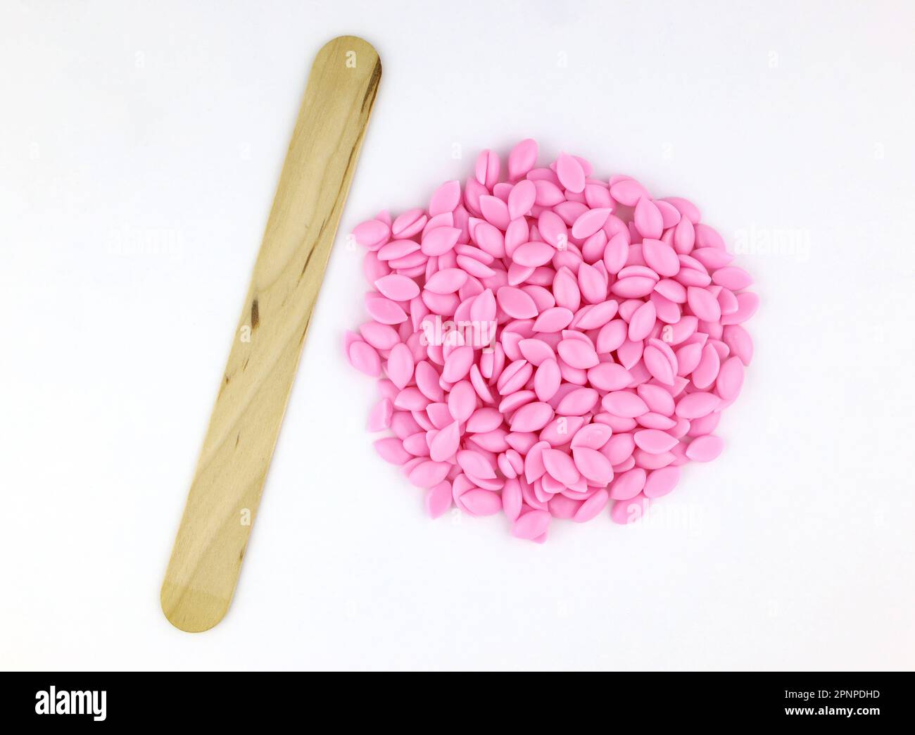 Beautiful pink depilatory wax granules and wooden spatulas on a white ...