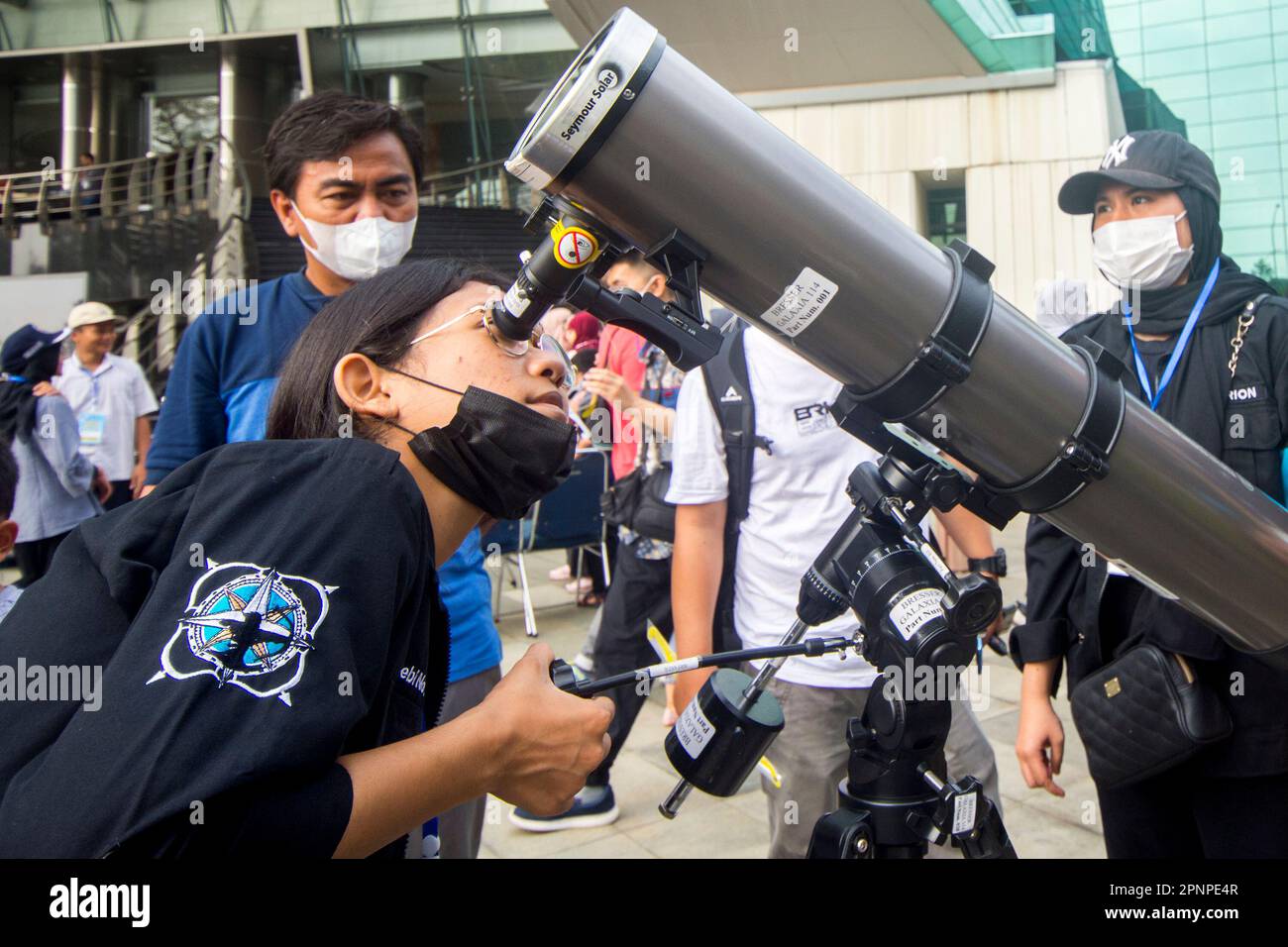 A man watch hybrid partial solar eclipse with telescope in Jakarta, Indonesia on April 20, 2023 ...