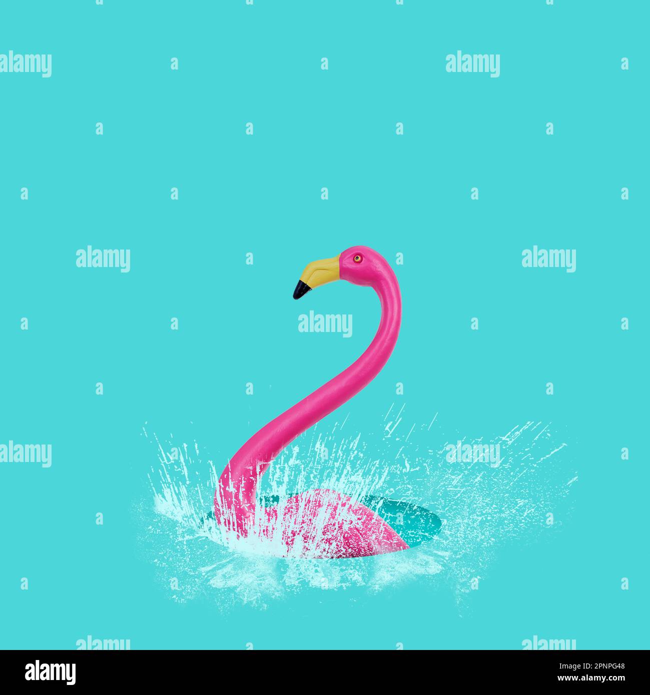 closeup of a fake pink flamingo splashing in a puddle of water, on a ...