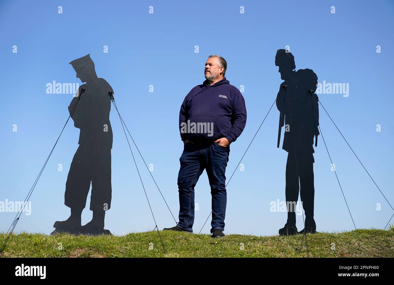 Dan Barton, creator of Standing with Giants, stands next to silhouettes ...