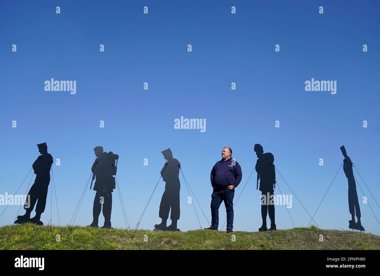Dan Barton, creator of Standing with Giants, stands next to silhouettes ...