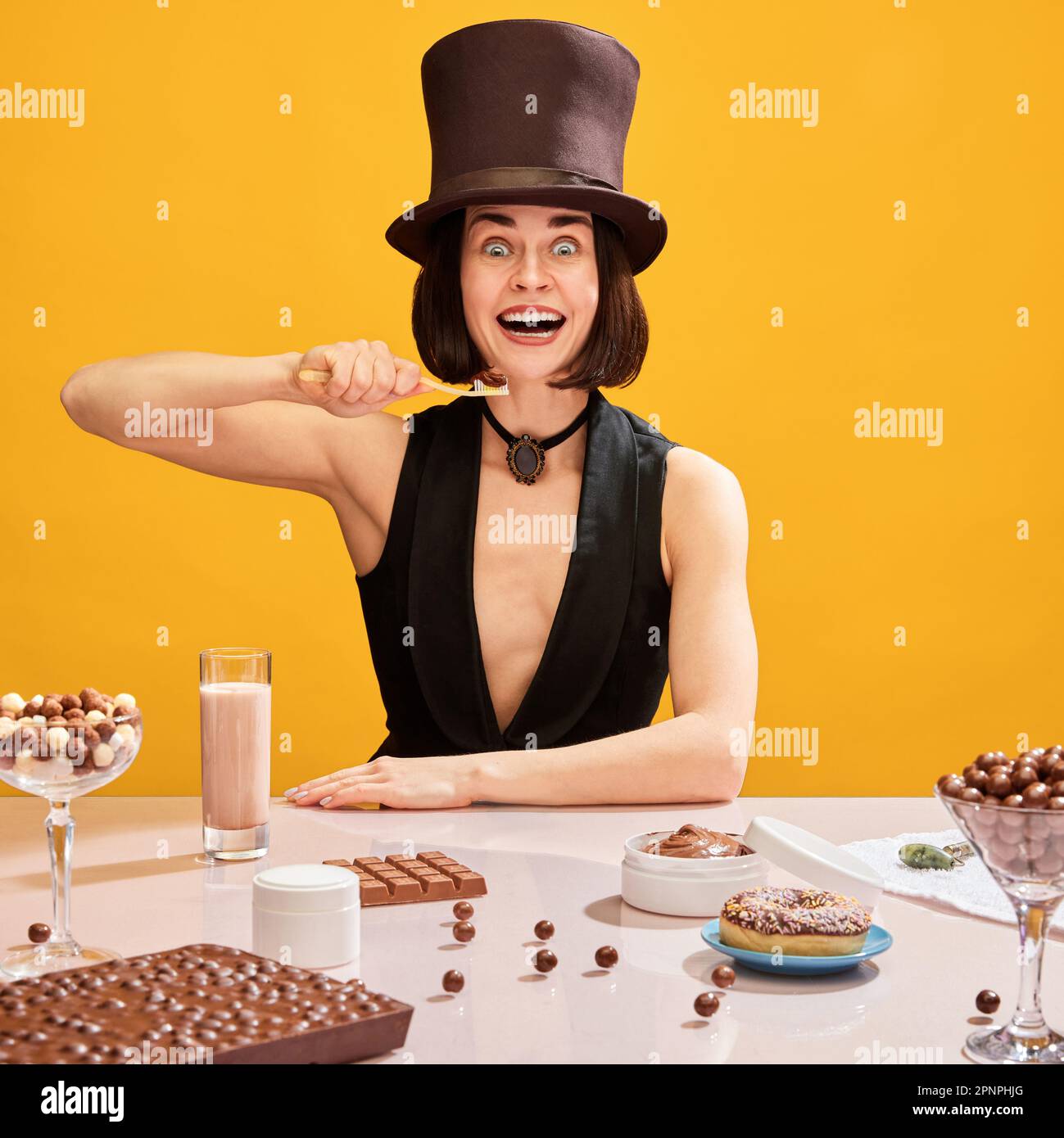 Crazy looking, smiling woman in cylinder brushing teeth with chocolate ...