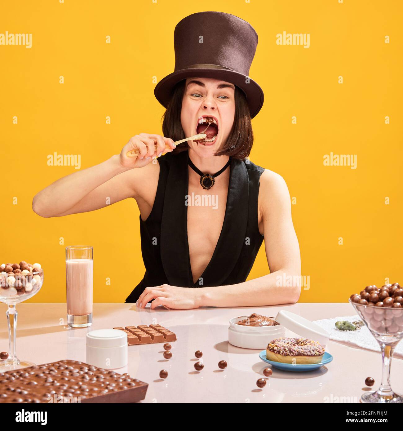 Crazy looking, smiling woman in cylinder brushing teeth with chocolate ...