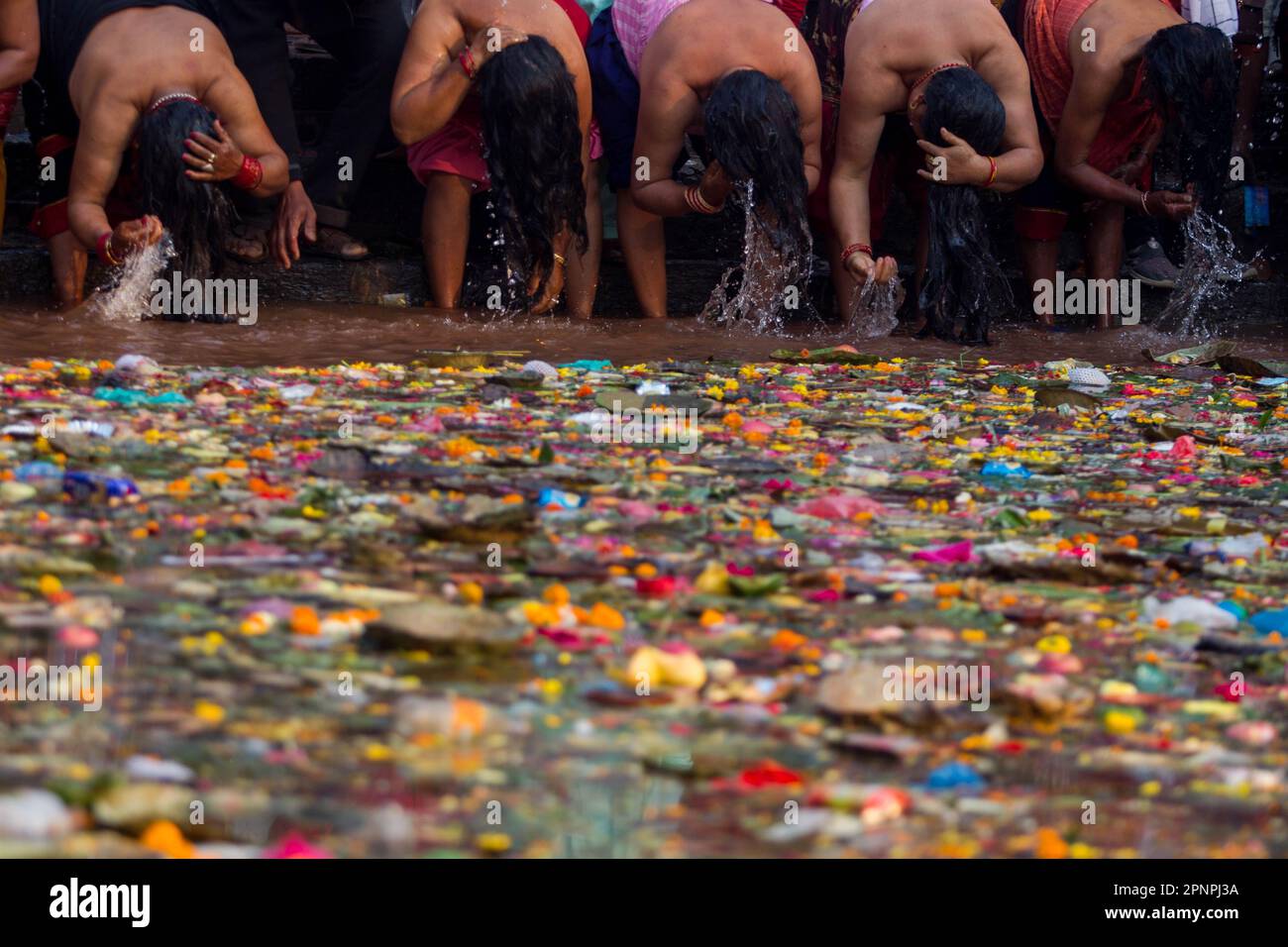 Kathmandu, Nepal. 20th Apr, 2023. People take a holy bath beside a pond ...