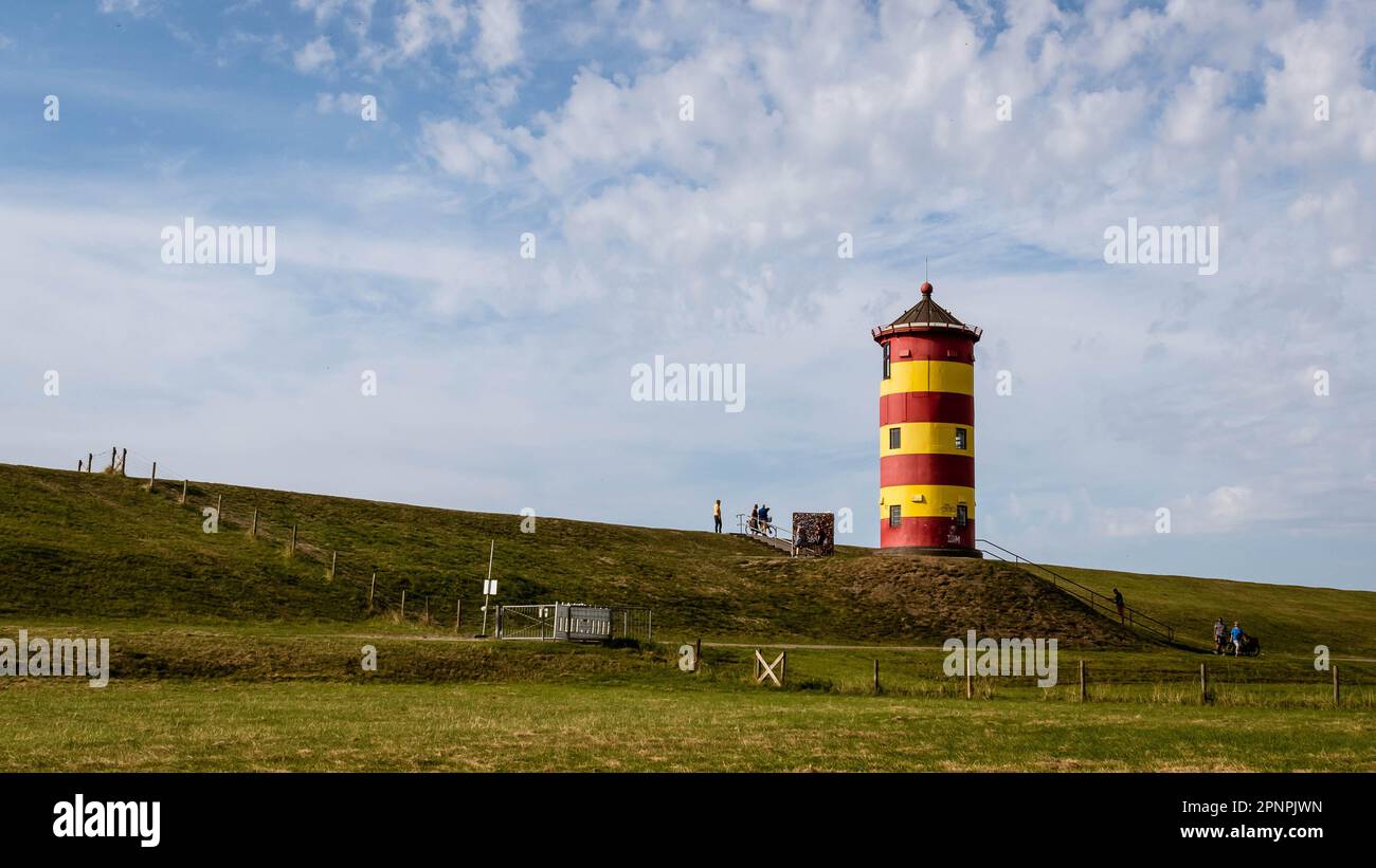 An idyllic scene of Pilsum lighthouse atop a grassy hillside surrounded ...