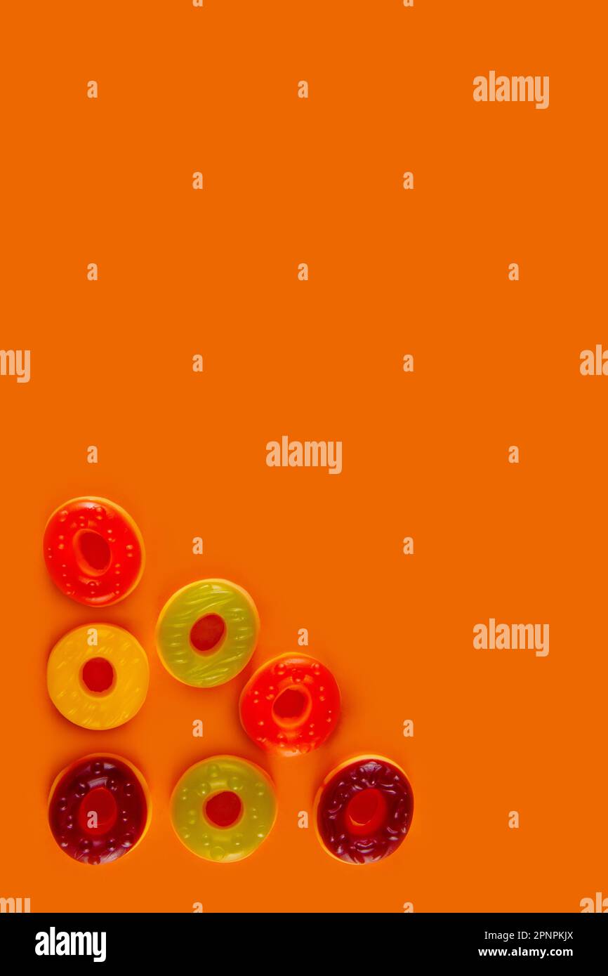 Triangle of round jelly candies at the corner of orange background ...