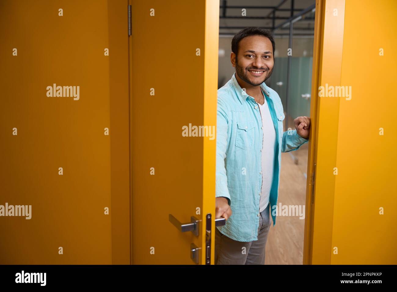 Portrait of Hindu male inviting you to enter office Stock Photo - Alamy