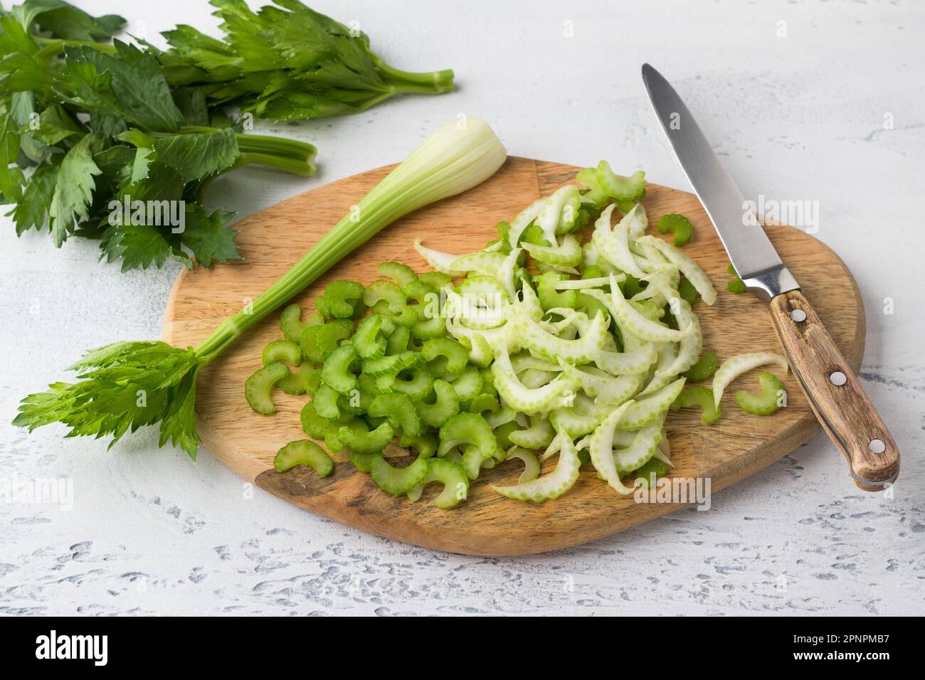 Wooden board with chopped stalk celery on a light blue background, top ...
