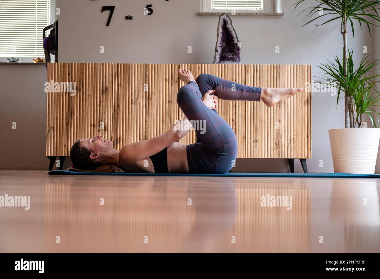 Fit young woman in a sportswear lying on her back on an exercise mat ...