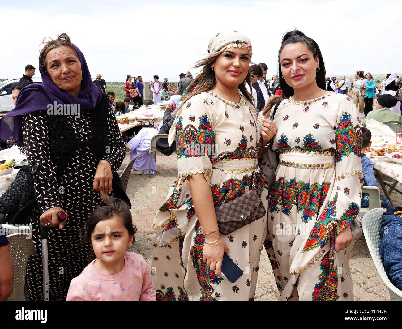 Two young women and their mothers in traditional clothes participate in ...