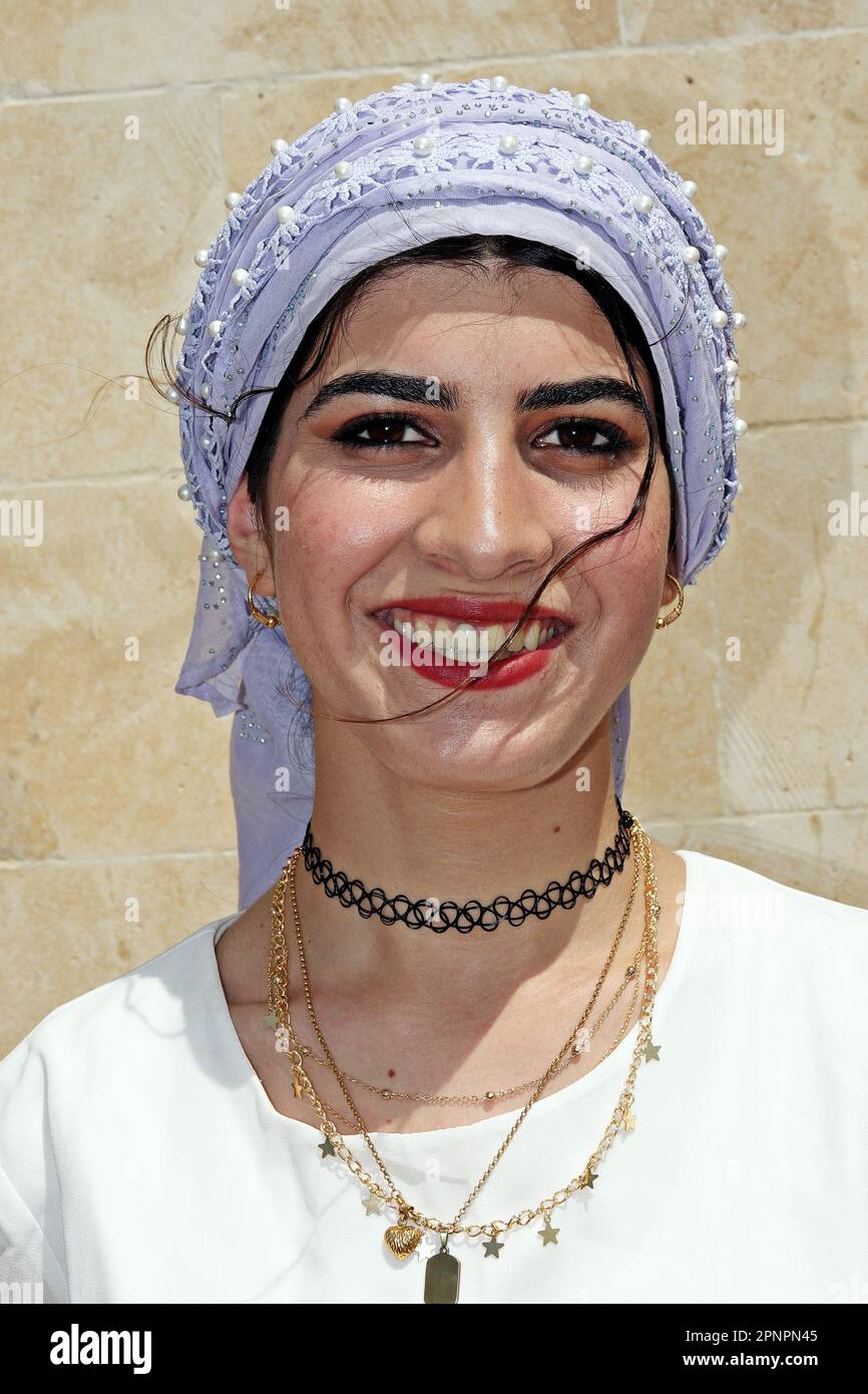 A Yazidi woman in colorful clothes is seen participating in the ...