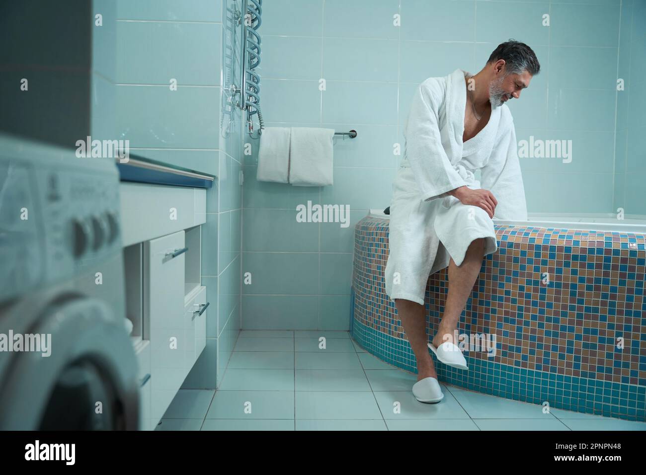 Man is going to take bath, checking water temperature Stock Photo - Alamy