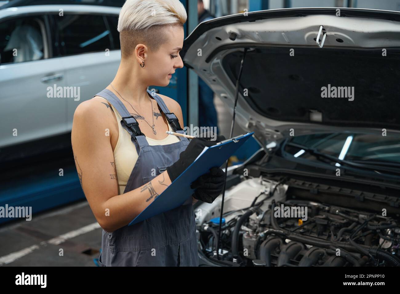 Beautiful lady mechanic diagnosing car in auto service Stock Photo - Alamy
