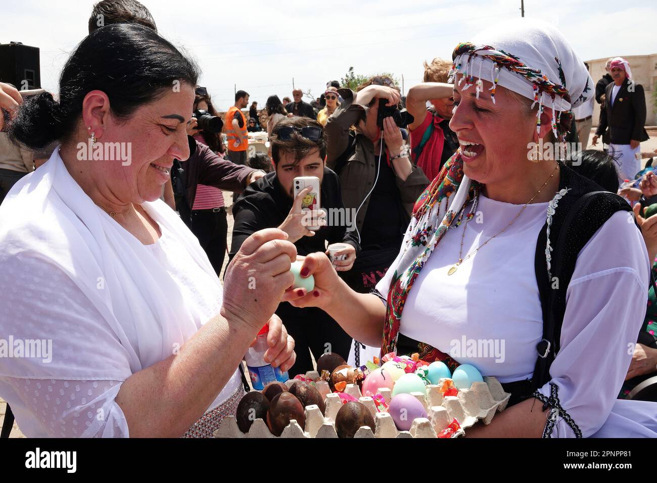 Two Yazidi women are seen joyfully swapping painted eggs during the ...