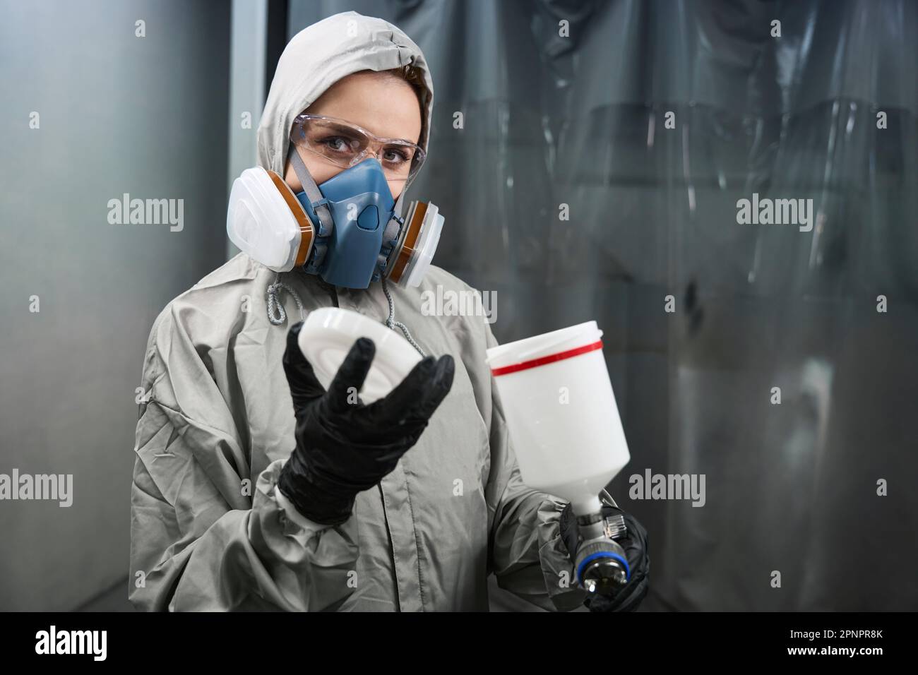 Experienced woman mechanic facing camera while working in painting ...