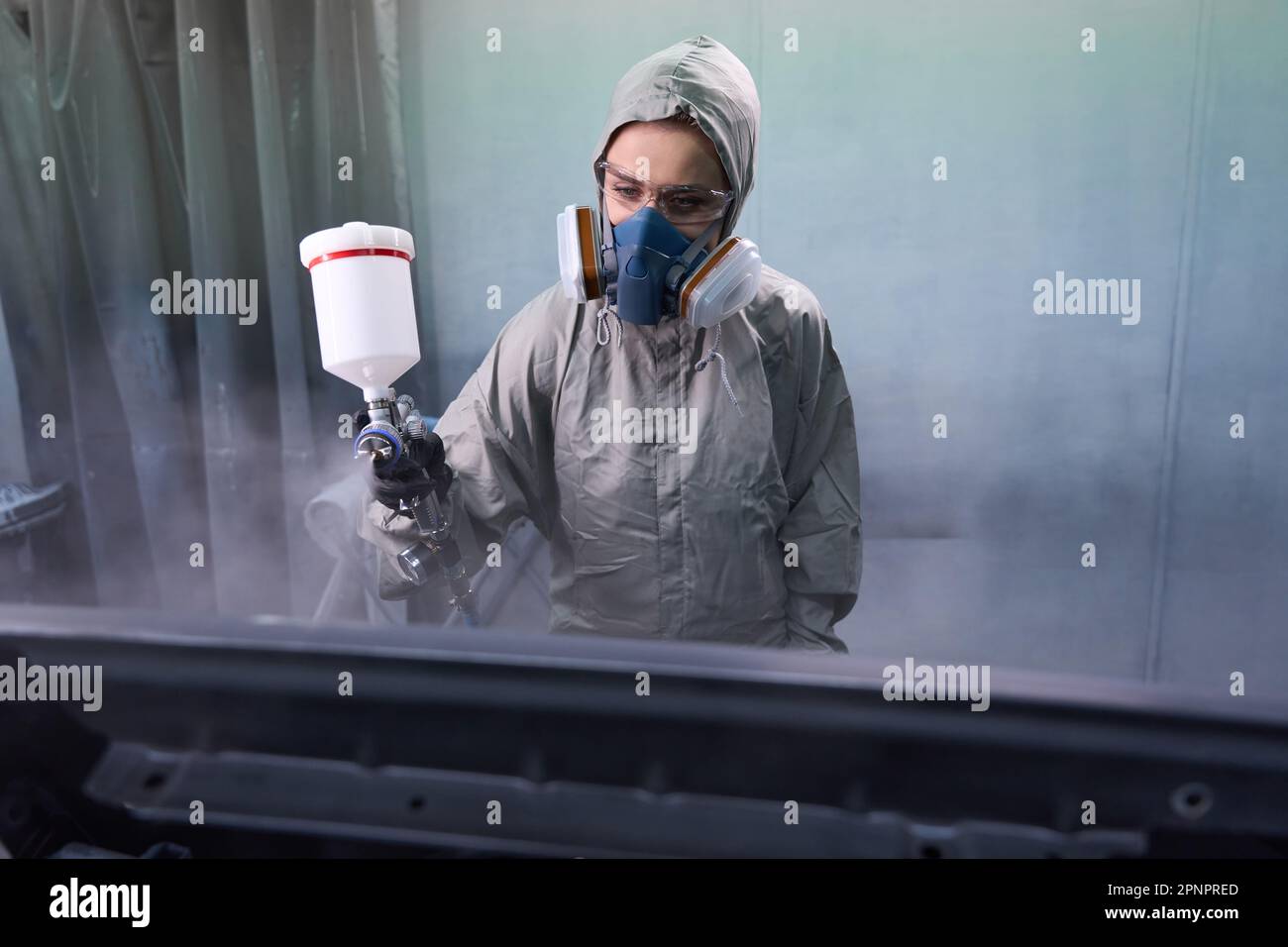 Experienced woman mechanic painting car at conventional garage Stock ...
