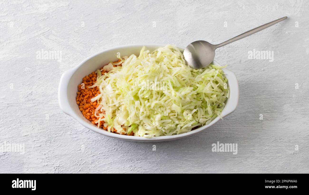 Ceramic mold with red lentils and white cabbage on a light gray ...