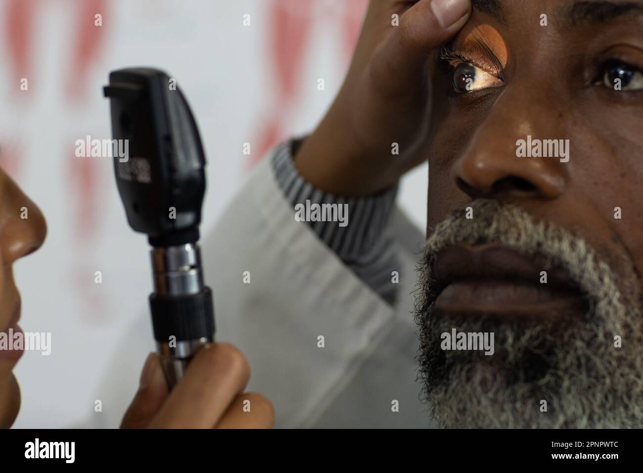 Biracial female doctor using funduscope and examinating african ...
