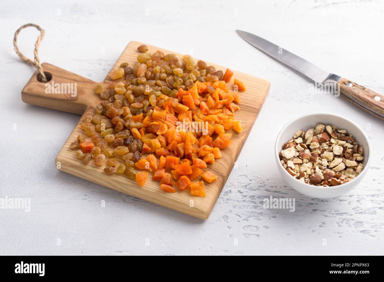A wooden board with dried fruits - raisins and chopped dried apricots ...