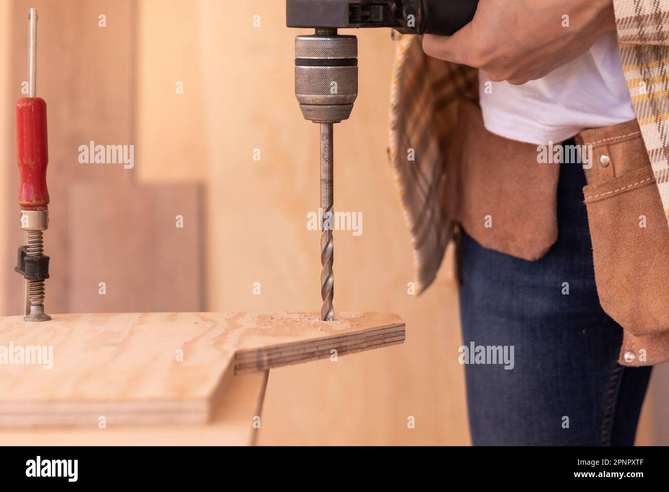Crop carpenter drilling hole in wooden plank with electric screwdriver ...