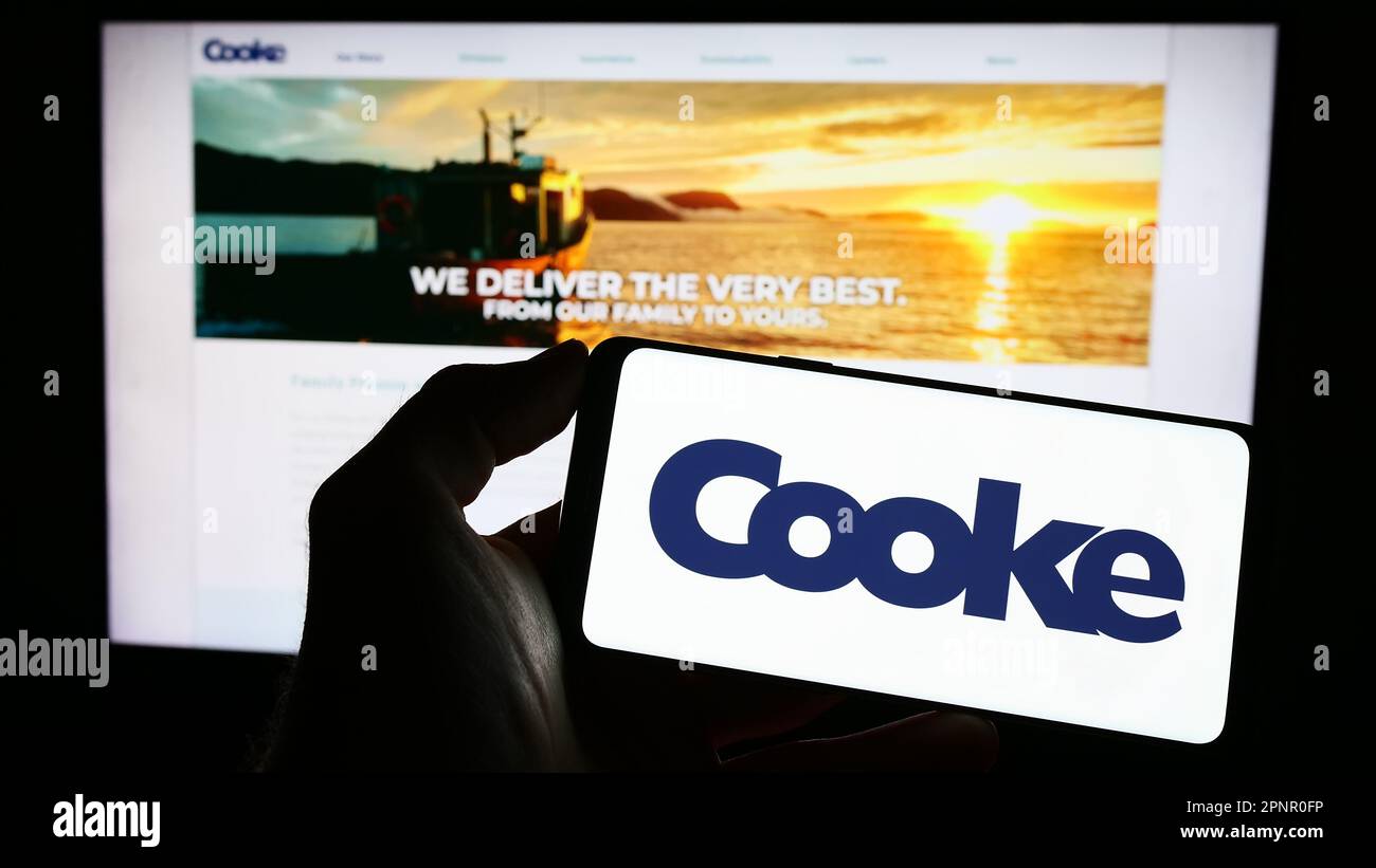 Person holding mobile phone with logo of Canadian seafood company Cooke ...