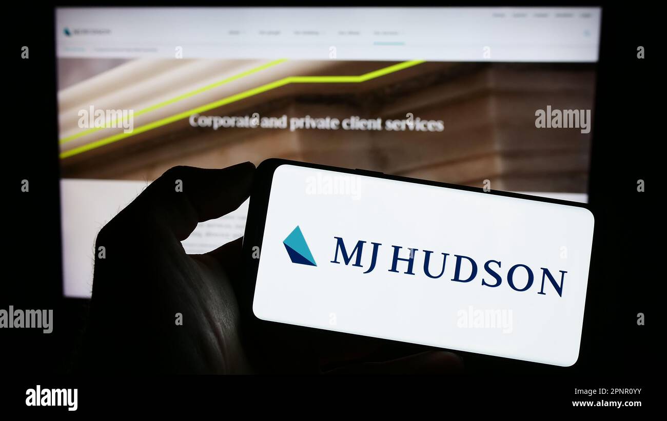 Person holding mobile phone with logo of British financial company MJ ...