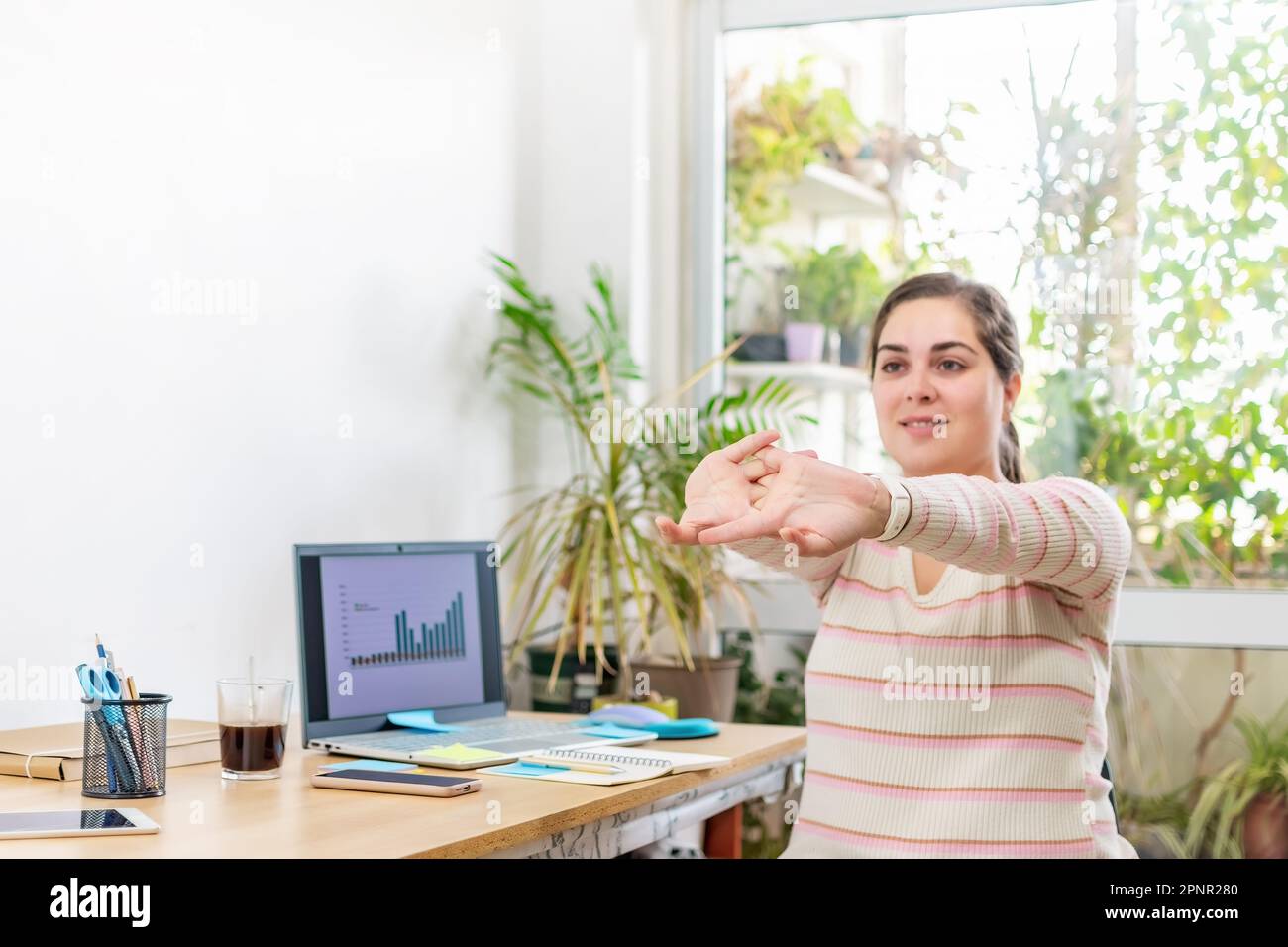 A woman stretching and exercising in an office setting, seeking relief ...
