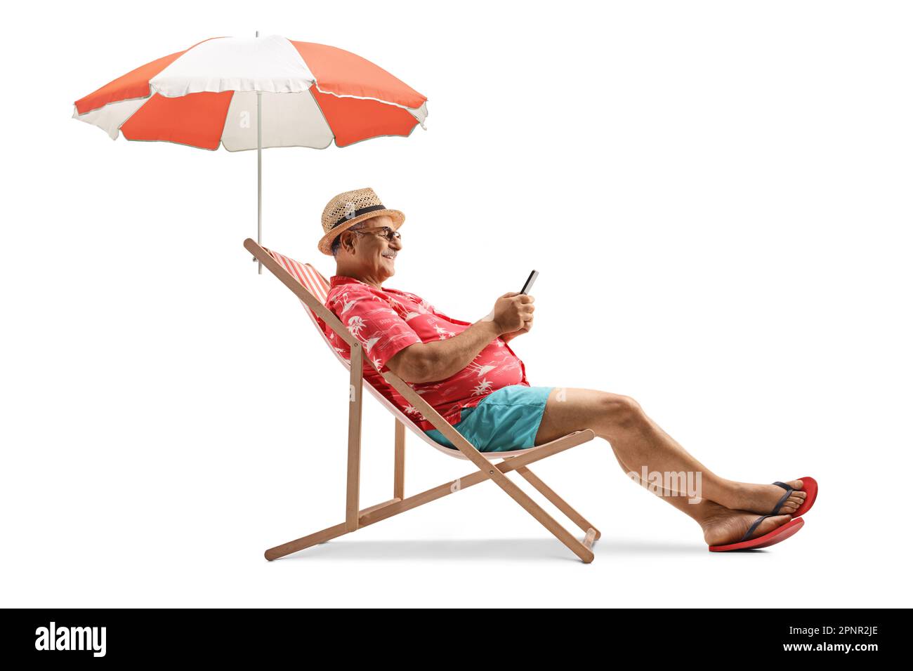 Mature man sitting on a beach chair under umbrella with a smartphone ...