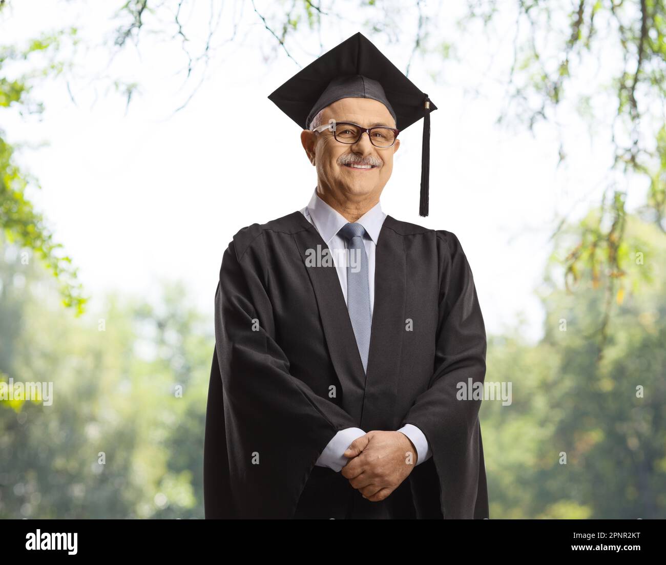 University dean wearing a black graduation gown and posing outdoors ...